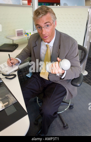 Adult businessman lifting weights at his desk Stock Photo - Alamy