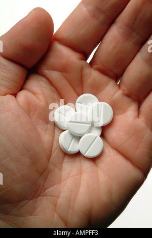 Many white tablets in the palm of hand on blue background. Medical ...