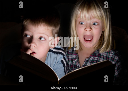 children reading book by torchlight at bedtime Stock Photo - Alamy