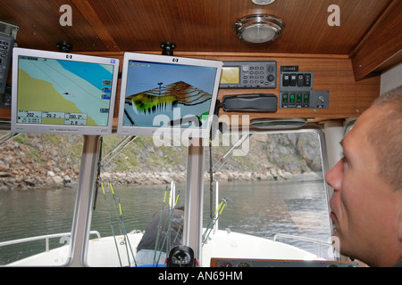 Boat captain watches his instruments while guiding boat to cod fishing ...