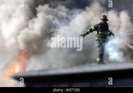 Firefighter on a roof fighting a fire Stock Photo - Alamy