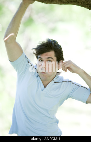 Man making silly monkey face isolated on grey background. Guy grimaces ...