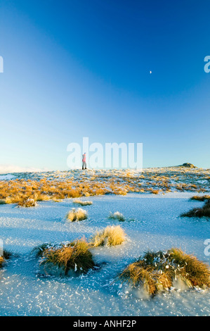A walker on a frozen tarn on the summit of Red Screes in the Lake ...