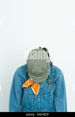 Teen girl wearing overalls and cap, covering face, side view Stock ...