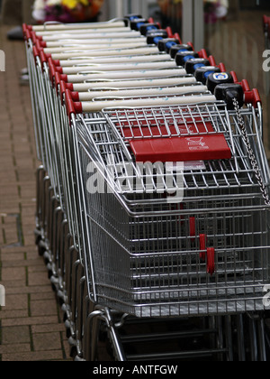 Row of stacked metal shopping trolley carts with yellow handles near of ...