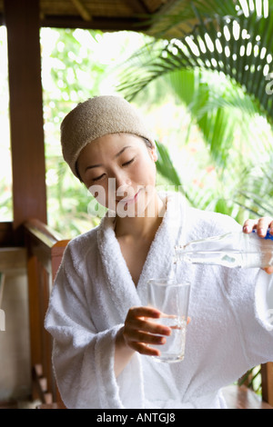 Young woman pouring water into glass on blue background Stock Photo - Alamy
