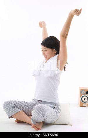 Asian woman stretching arms while sitting on sofa at bright modern home ...