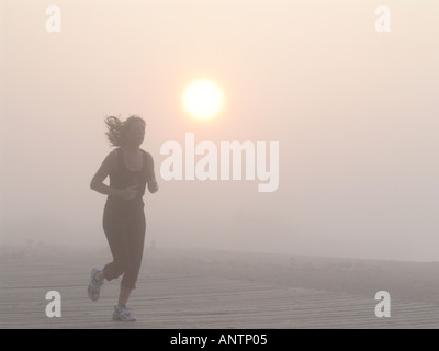 a female runner jogs at the beach at sunrise Stock Photo - Alamy