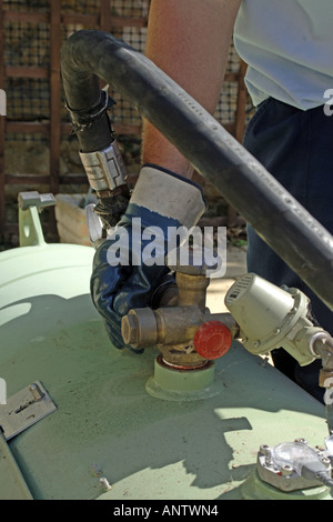 LPG Gas delivery man venting the tank of air as he fills the tank with ...