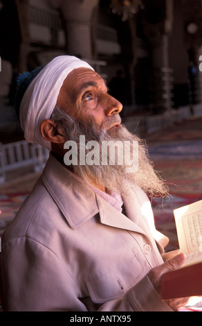 Praying Muslim man with Koran on dark background Stock Photo - Alamy