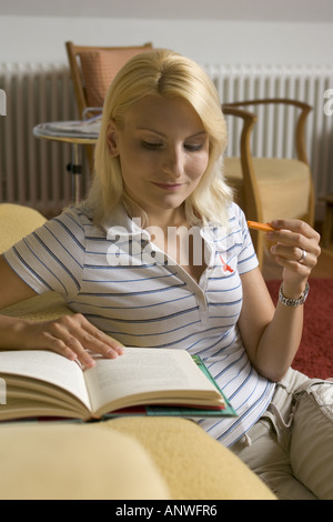 Young woman eating while she reads a book Stock Photo - Alamy
