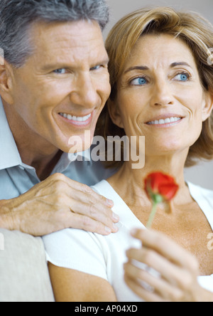 Hand holding red rose bud in garden with green bokeh background, person ...