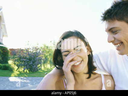 Young woman sniggering or giggling into her hand in a close up cropped ...