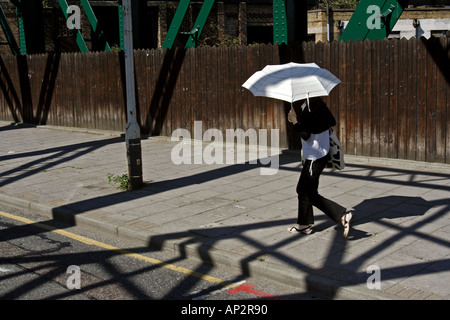 A woman shields herself from the sun with an umbrella as she walks in ...