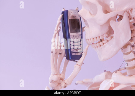 Human skeleton with mobile phone in hand lies in bed, black humor ...
