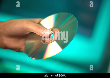 Hand holding cd infront of computer screen Stock Photo - Alamy