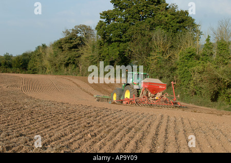 Tractor with drill and power press planting barley crop in red Devon ...