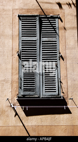 Window with wooden green shutters and a red windowsill in an old stone ...