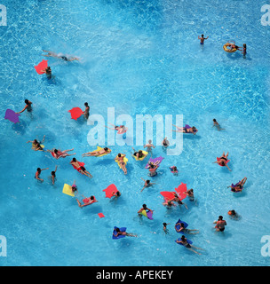 Vacationers in large swimming pool and others lounging on chairs near ...