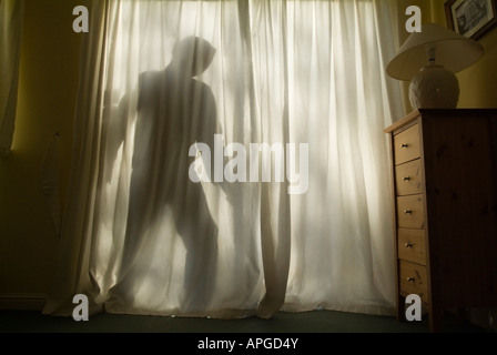 Image of a suspicious man behind the glass doors and curtains of a ...