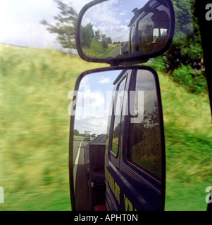 Drivers view of lorries in wing mirror of a car on a busy motorway in ...