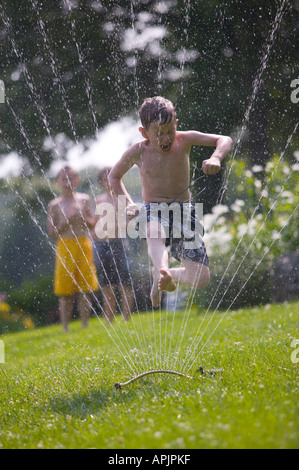 Family Running Through Garden Sprinkler Stock Photo: 54244843 - Alamy