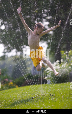 Family Running Through Garden Sprinkler Stock Photo - Alamy