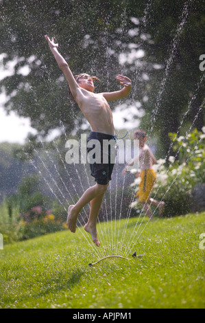Family Running Through Garden Sprinkler Stock Photo - Alamy