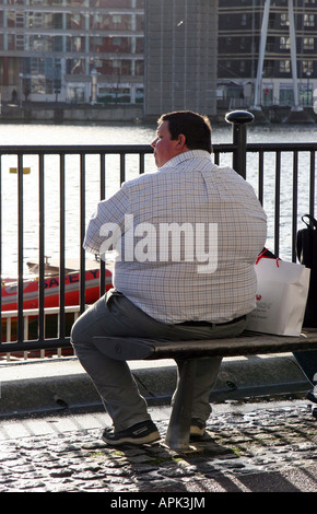 Fat man sitting on bench with his back and looking away Stock Photo - Alamy