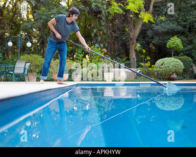 Young man is cleaning the swimming pool from underwater with a brush ...