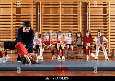 TEACHER SHOWING EXERCISE ON MAT TO PUPILS DURING GYM CLASS IN PRIMARY ...