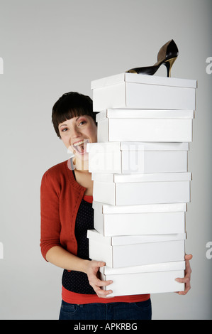 Young woman with shoe boxes and high heels on light background Stock ...