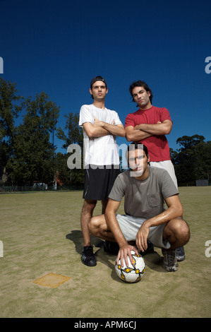 team of three friends playing football at the seaside Stock Photo - Alamy