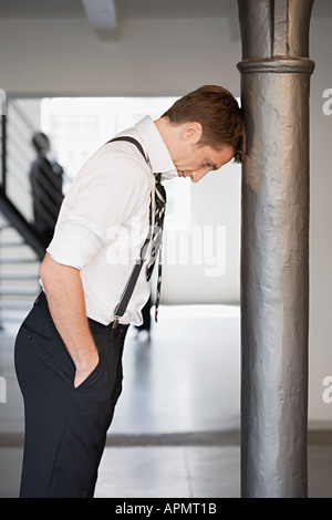 Businessman leaning against pole Stock Photo - Alamy