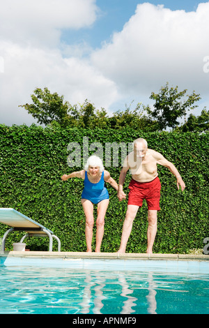 Senior couple jumping into pool Stock Photo - Alamy