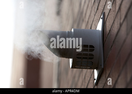 Steam coming out of a central heating flue on a house wall, England, UK ...