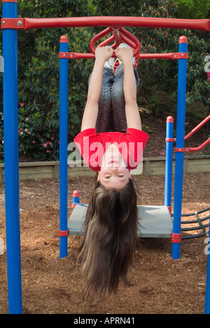 A young long haired girl is hanging from a tree tied up with ropes in ...