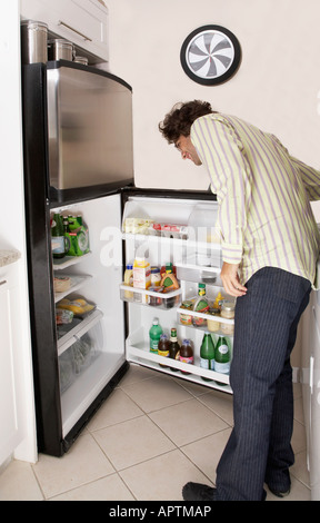 Adult man standing at refrigerator, choosing frozen convenience food in ...