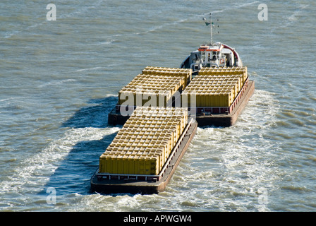 Looking down at tug boat pulling barges loaded with containers full of ...
