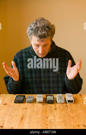 A man confused over which remote control to pick Stock Photo - Alamy