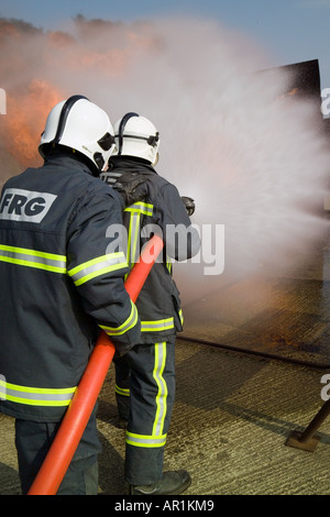 Firemen advancing fire behind water hose shield protection Stock Photo ...