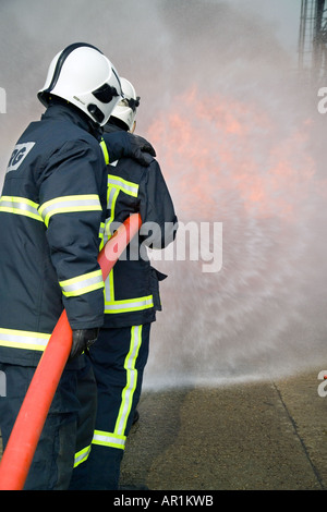 Firemen advancing fire behind water hose shield protection Stock Photo ...