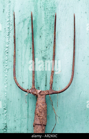 Rusty old pitchfork leaning against a fence Stock Photo - Alamy
