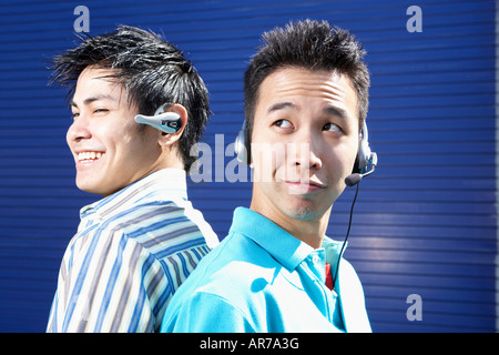 Two young people in headsets are smiling and talking to the clients ...