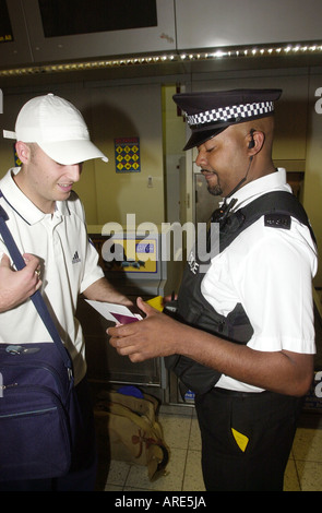 Police officer checks the details of a traveller at London Luton ...