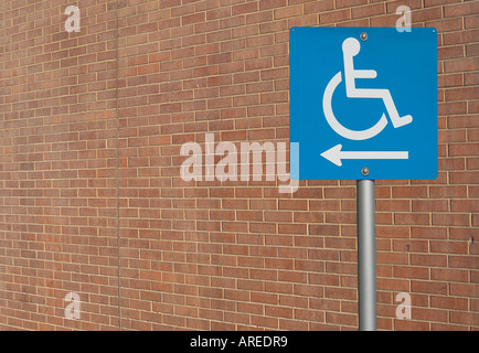 Wheelchair sign with arrow pointing left beside sign with a person ...