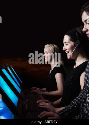 Call centre telephone operators with computer monitor screens at night ...