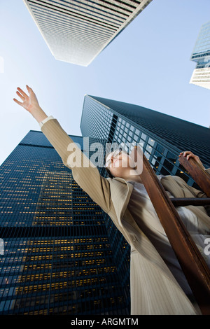 Businesswoman reaching upwards Stock Photo - Alamy