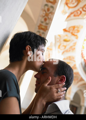 Low angle shot of a couple kissing during the sunset with a sunbeam in the middle of the two ...