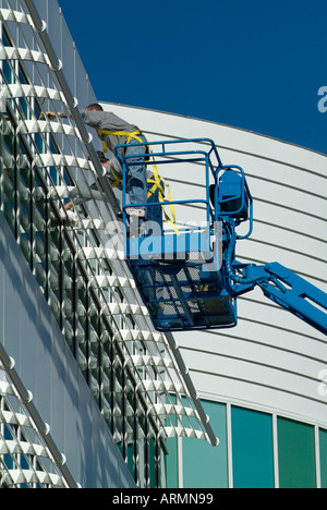 Window washers use mechanical industrial boom to elevate them against ...